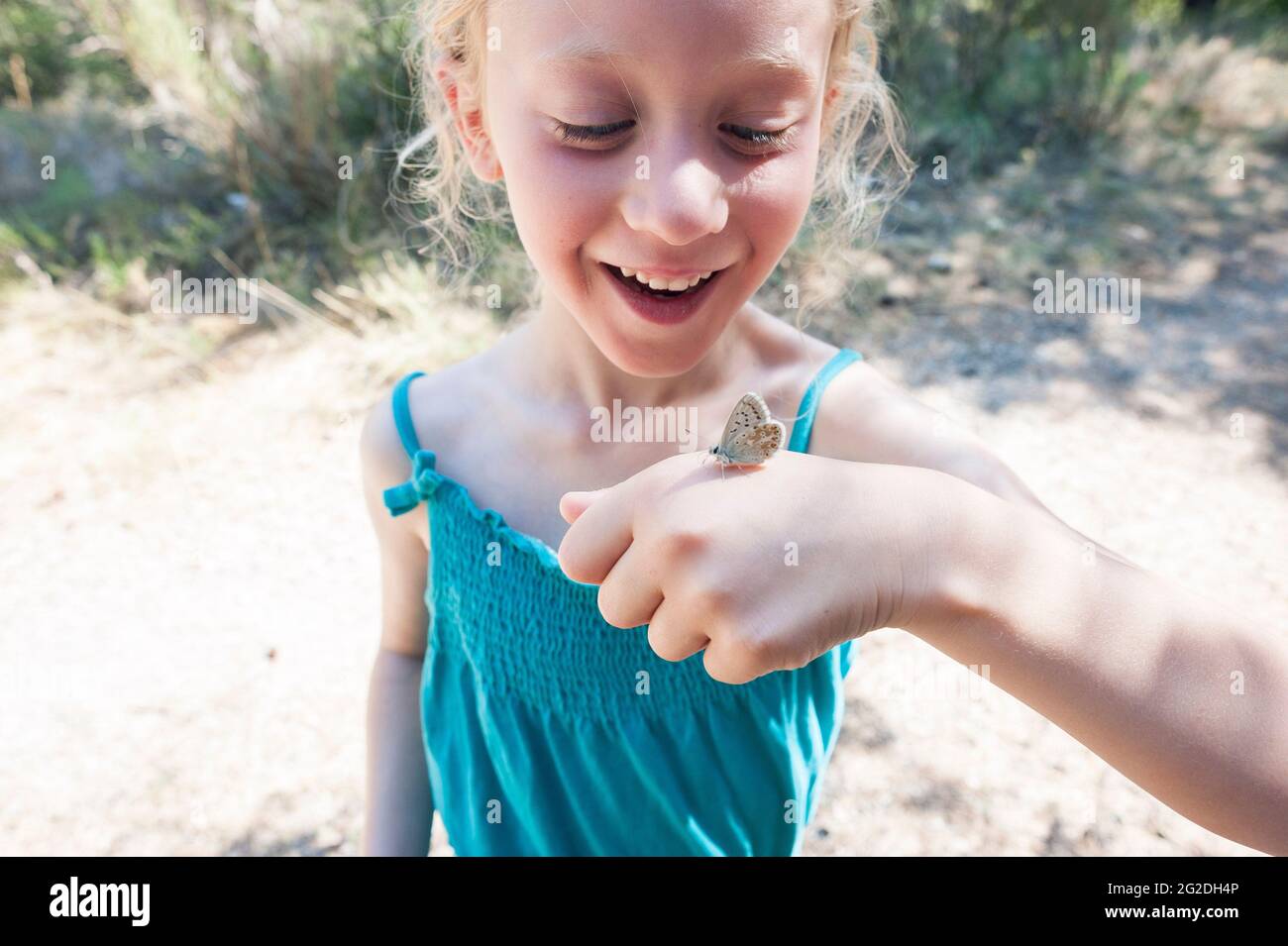 A butterfly lands on a young girls hand while she is out for a walk in ...
