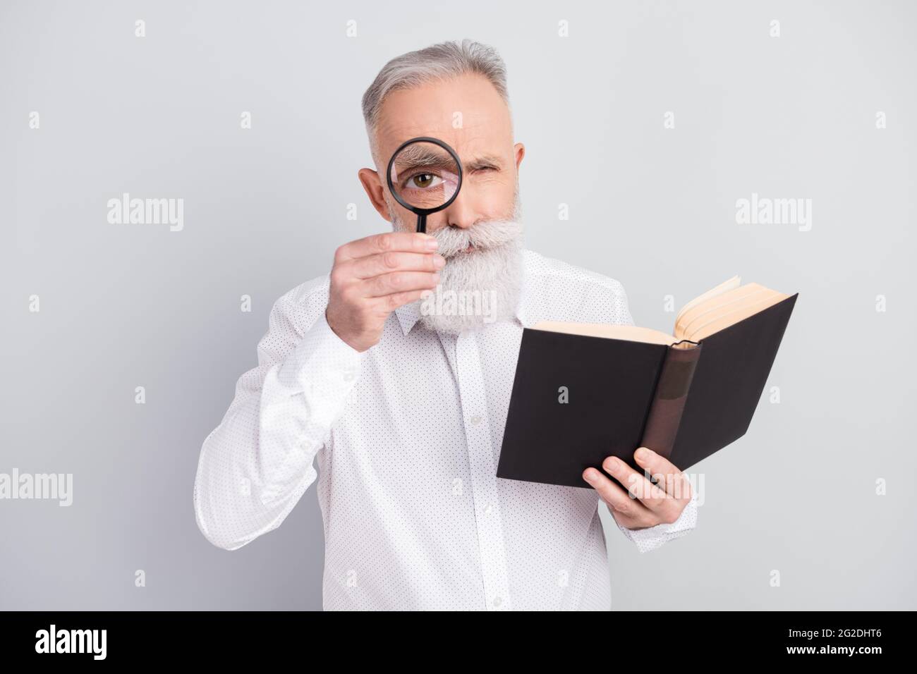 Photo of serious smart old man hold magnifier look eye book literature ...