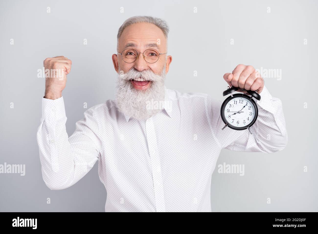 Photo Of Amazed Happy Cheerful Old Man Raise Hand Fist Hold Alarm Clock