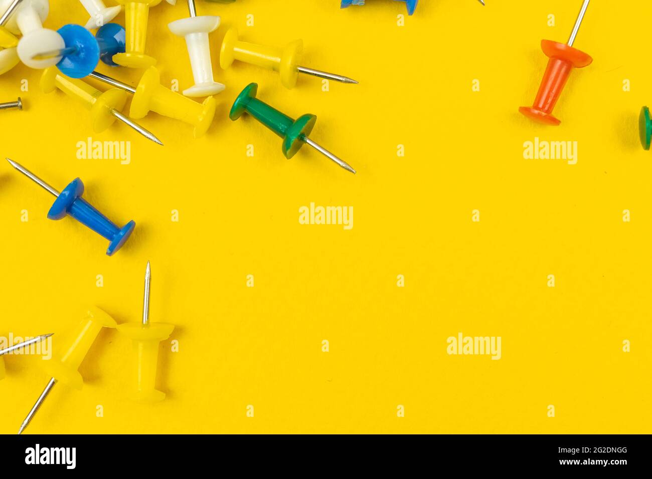 Yellow office desktop with a lot of colored push pins, border of school ...