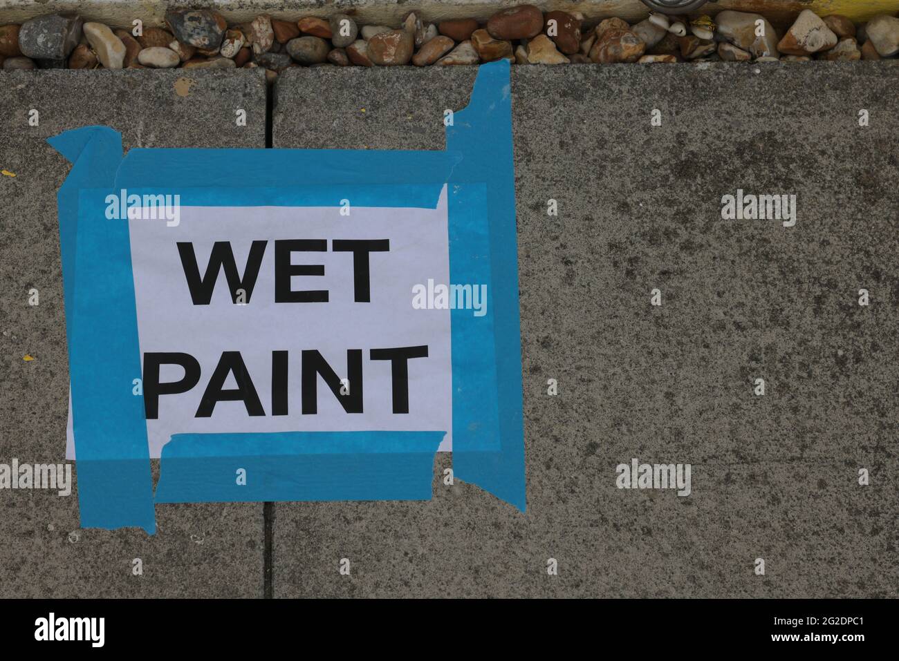 Board saying wet paint stuck to the pavement Stock Photo - Alamy