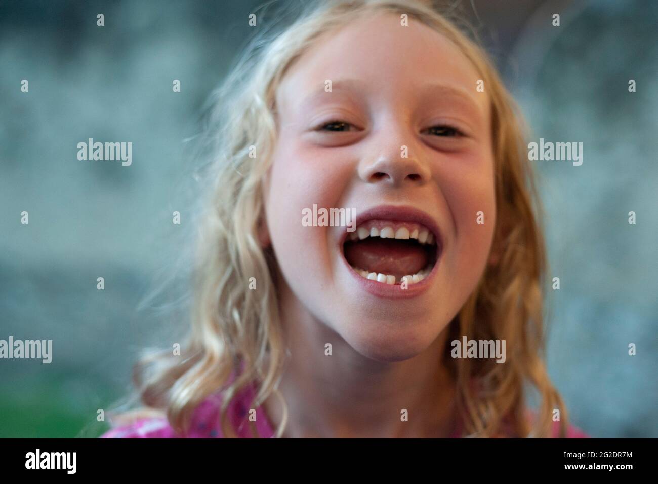 A young girl proudly shows off her mouth and the gap in her teeth where ...