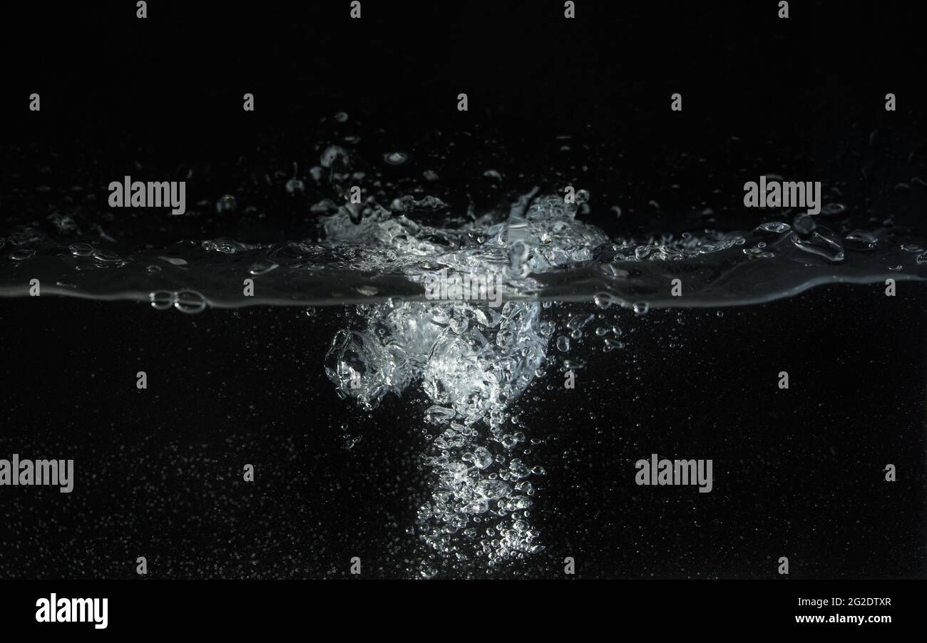 Water splashing as it's poured into aquarium tank, black background ...