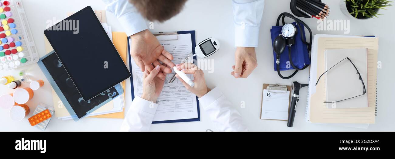 Doctor taking blood test from patients finger with lancet top view ...