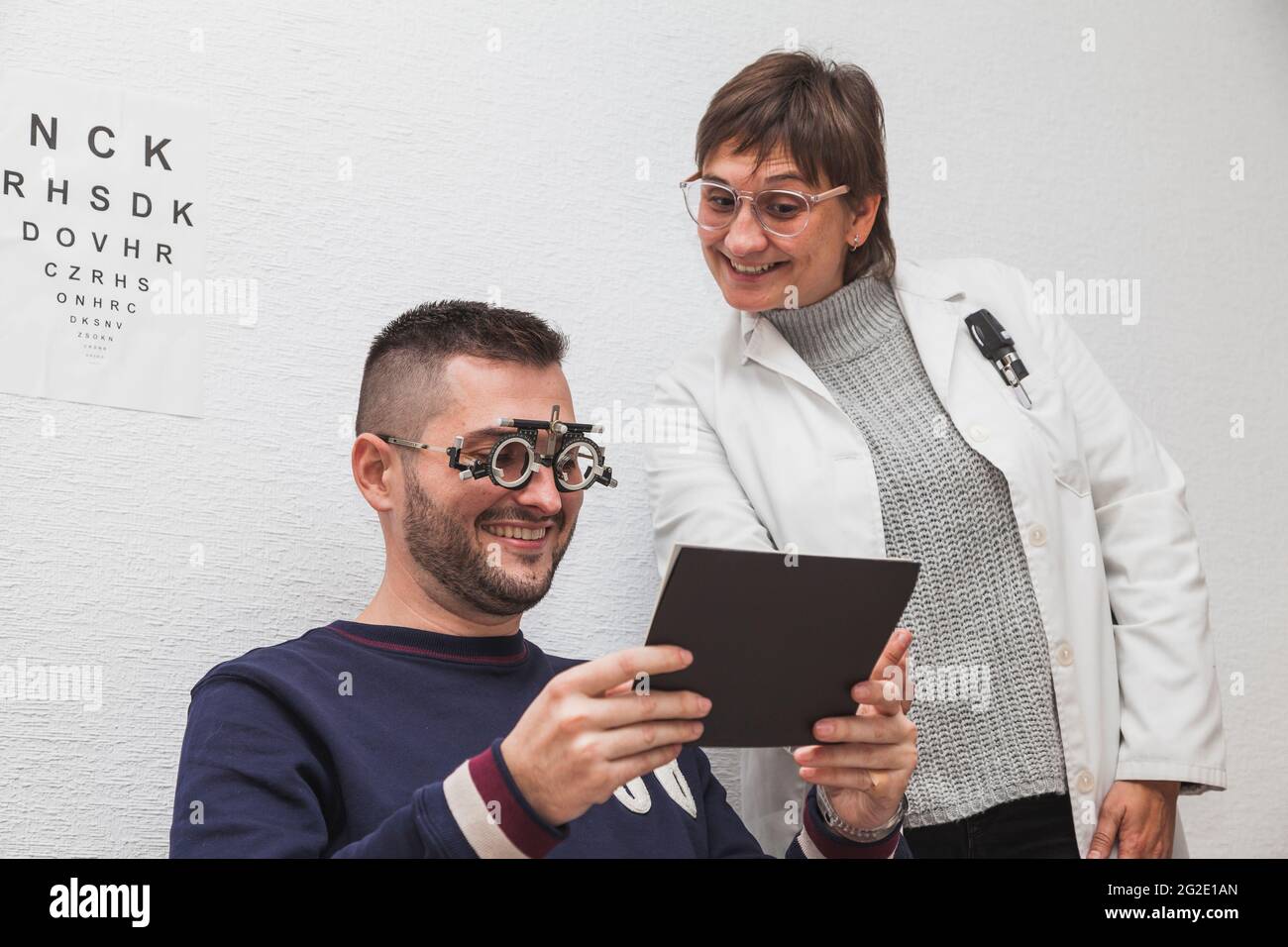 A patient at an optician follows the instructions of an optometrist to ...