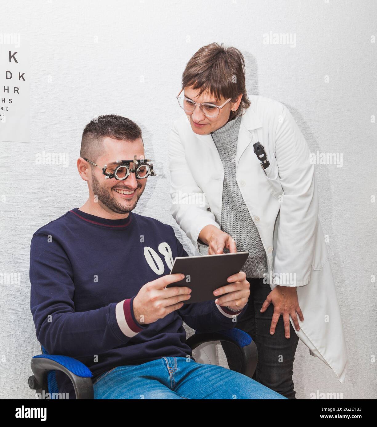A patient at an optician follows the instructions of an optometrist to ...