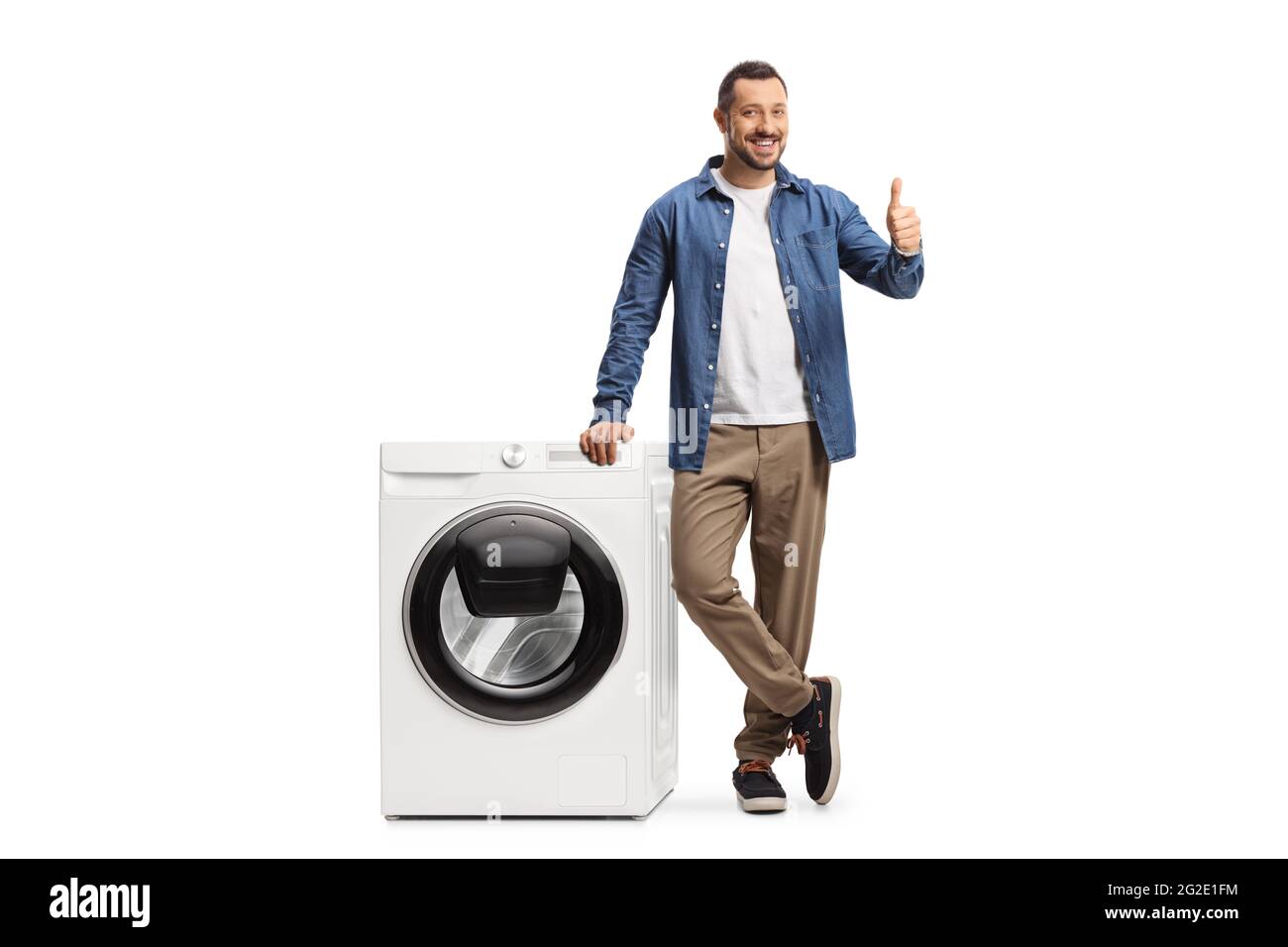 Young man standing next to a washing machine and showing thumbs up ...