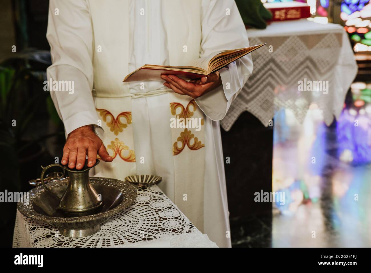 White-robed priest conducting a marriage with holy water and bible ...