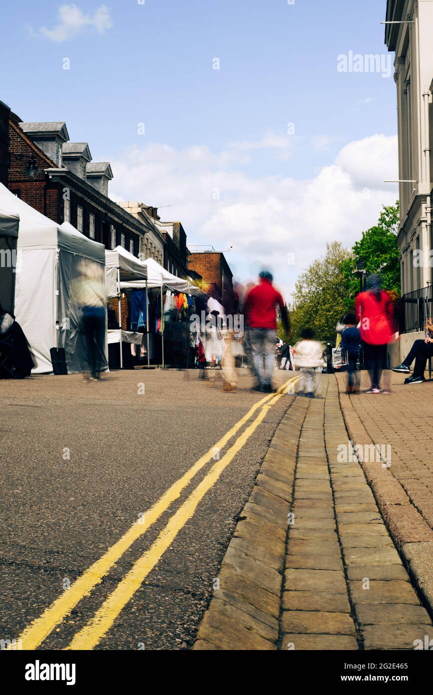 People walking through a high street market going shopping in town ...