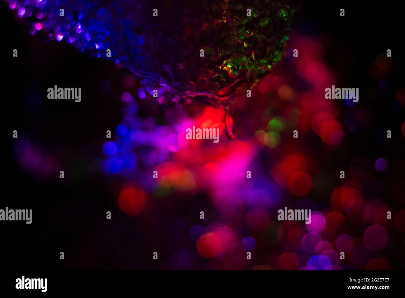 Colored water texture. Splashes of water lit in different colors. Close ...