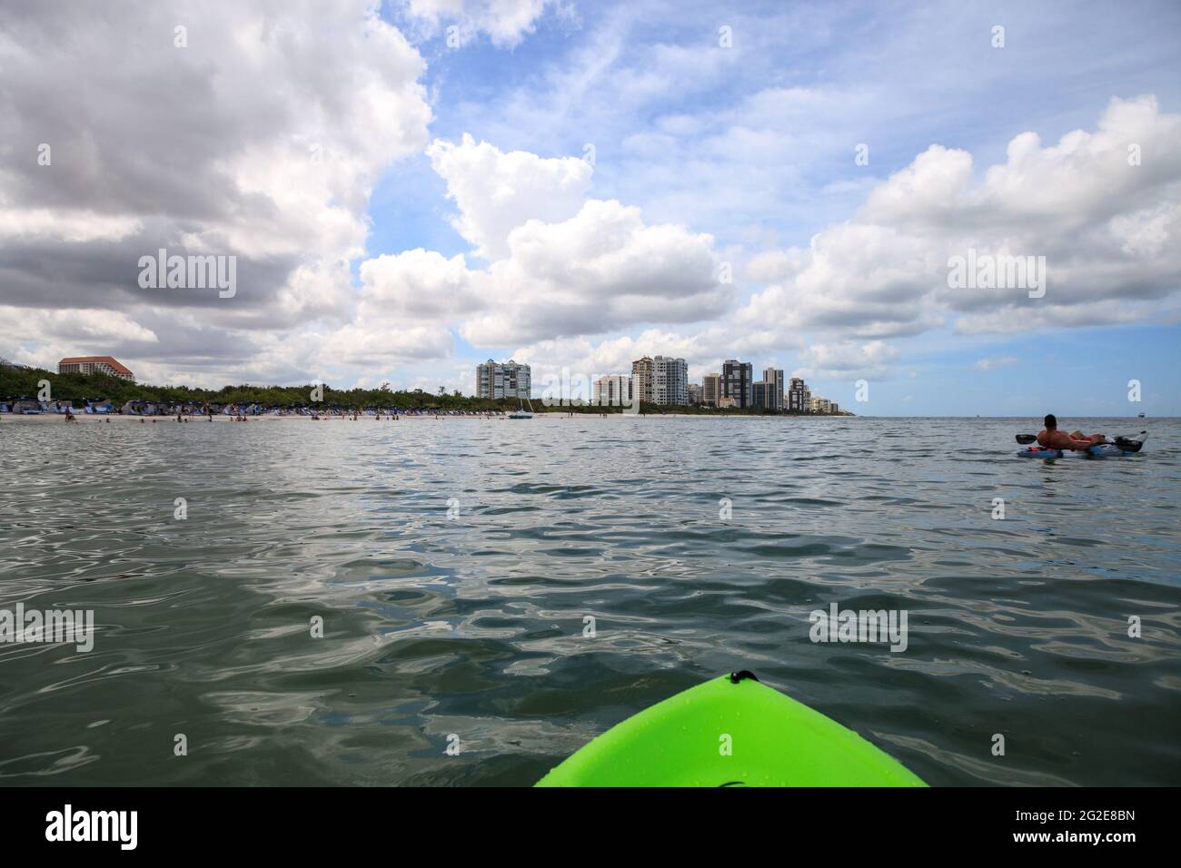 Man relaxes in a kayak on the ocean along Clam Pass beach in Naples ...