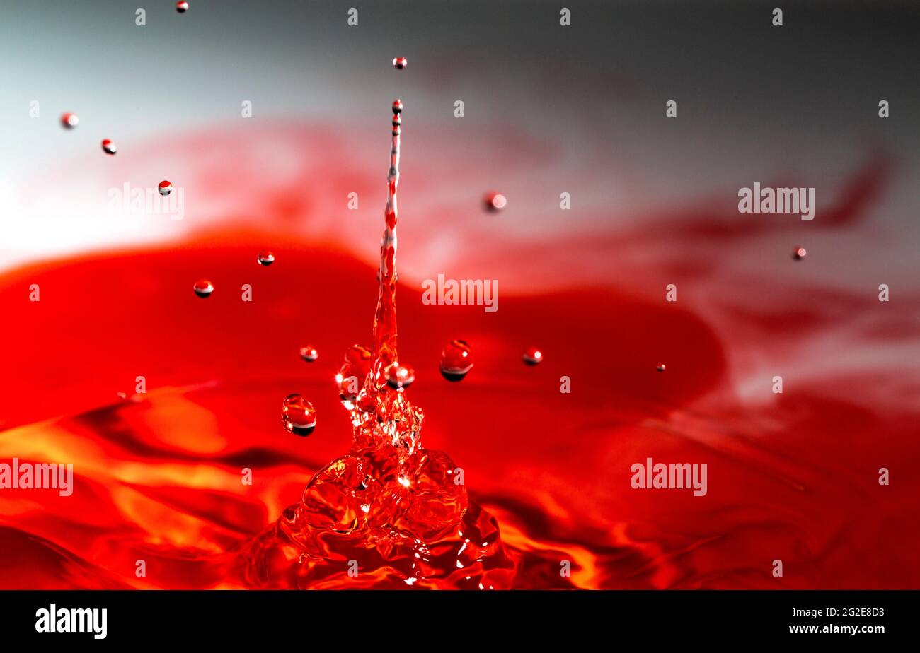 Clear water drop on a red tinted water Stock Photo - Alamy
