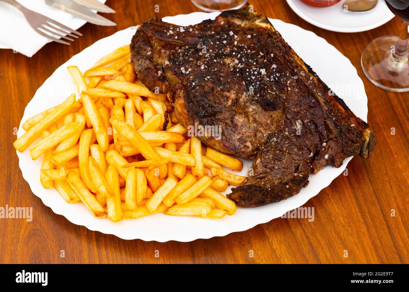 Roasted beef chop on bone with fries and sauce Stock Photo - Alamy