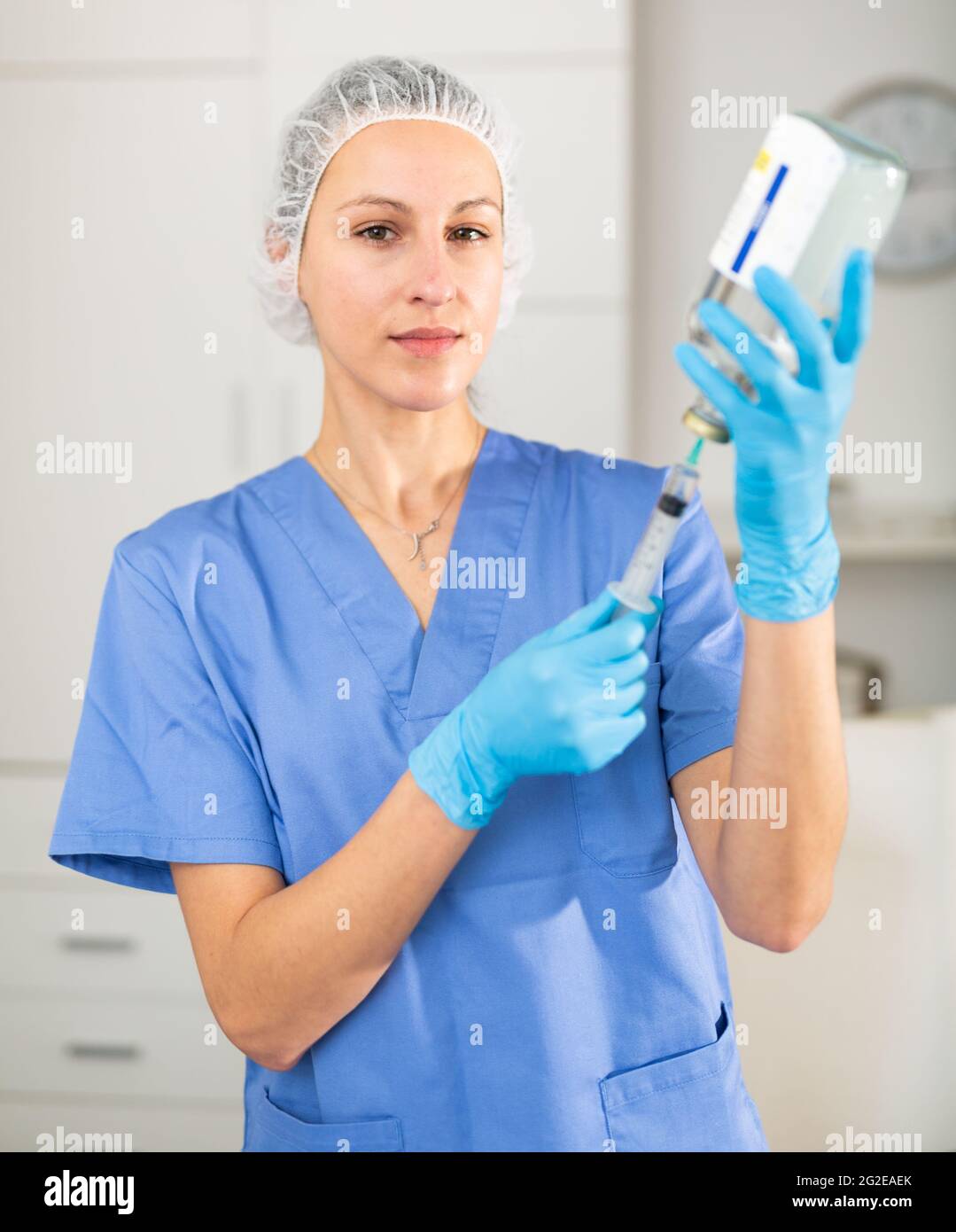 Experienced female nurse fills a syringe with medicine for injection in ...