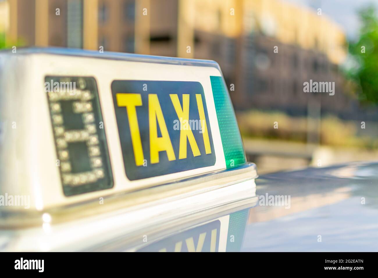 Illuminated "TAXI" sign on a cab with a block of buildings in the ...