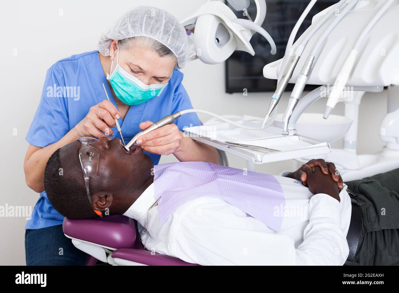 Dentist professional filling teeth for man patient sitting in medical ...