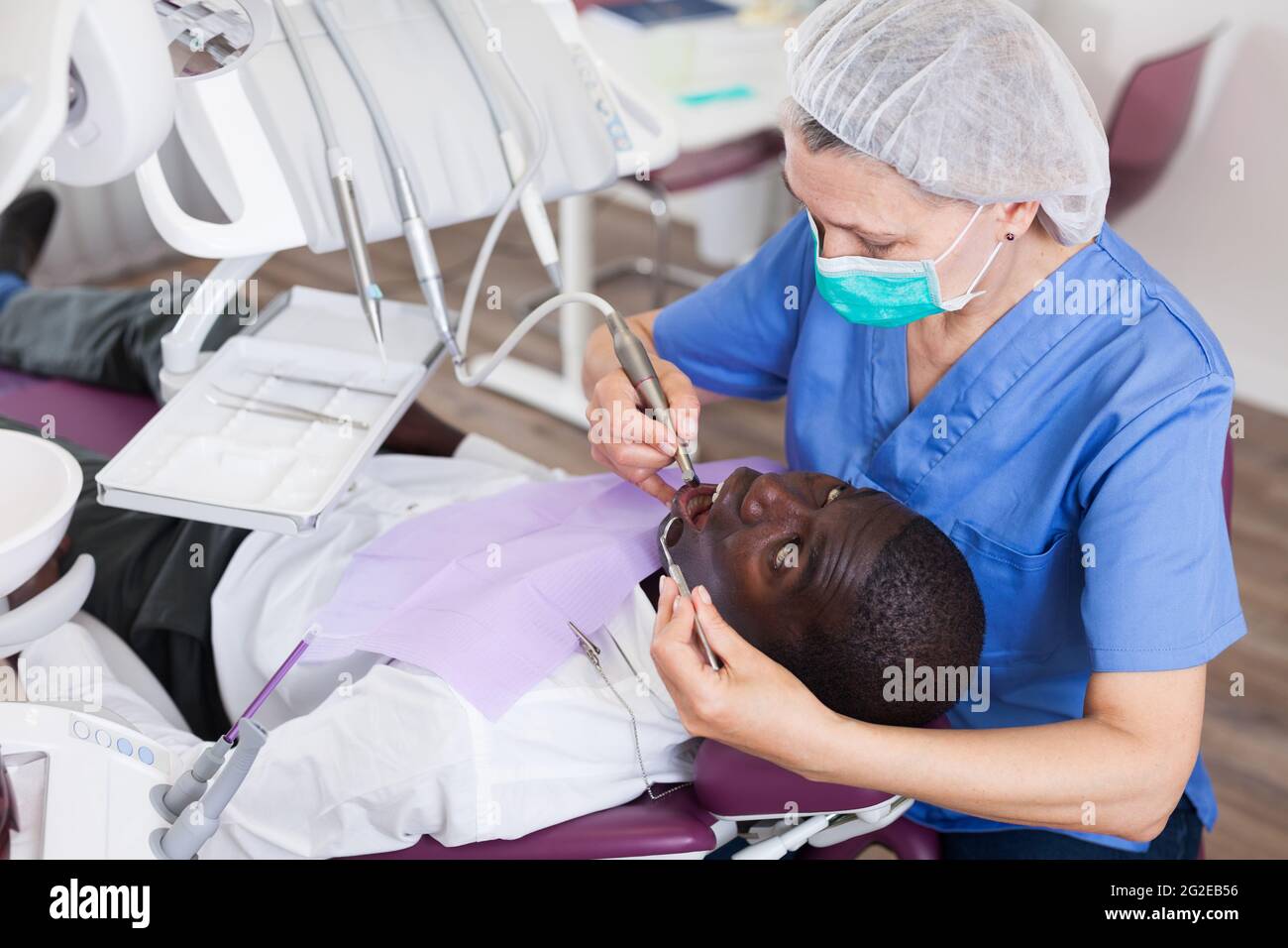 Dentist professional filling teeth for man patient sitting in medical ...