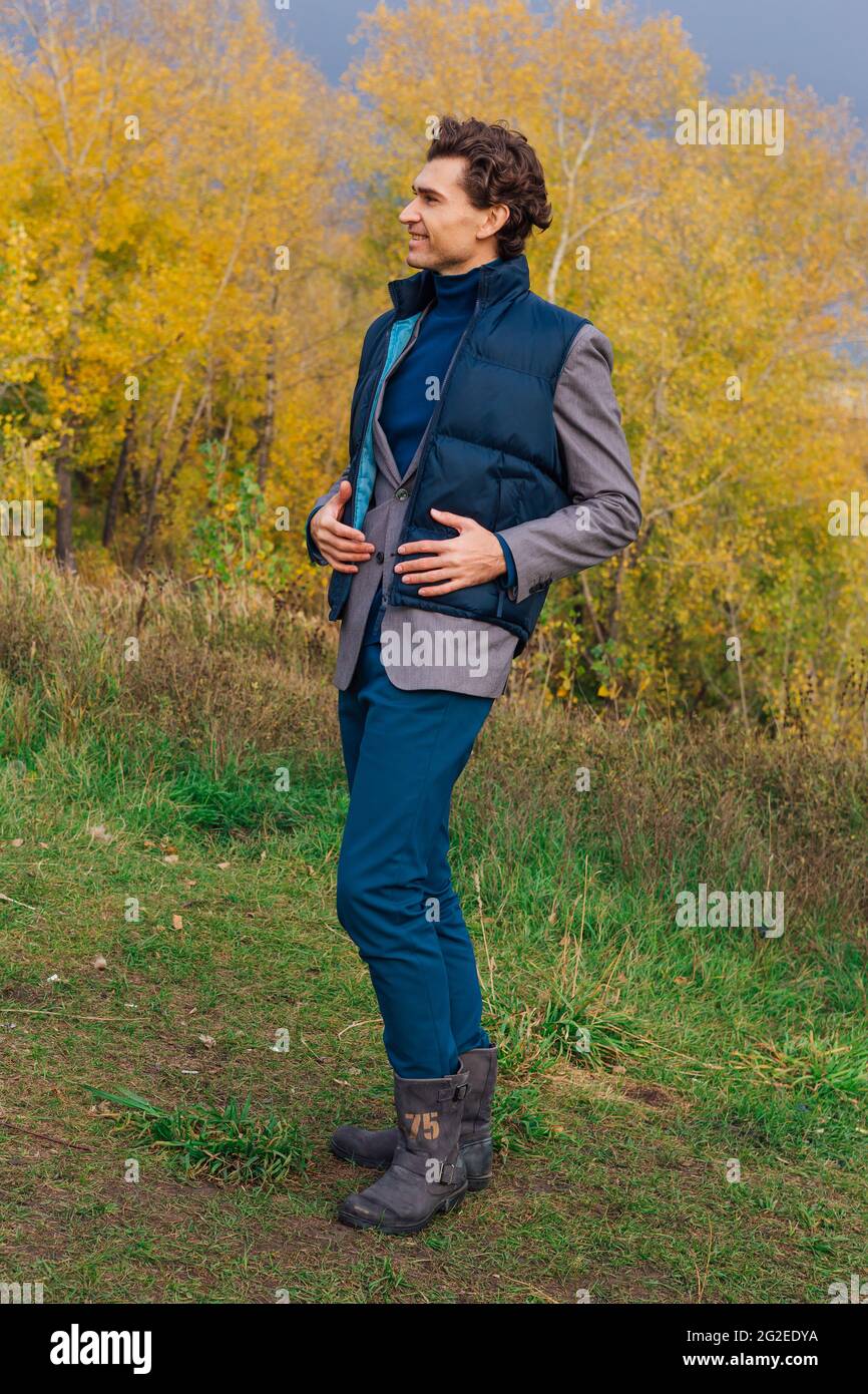 Tall handsome man walking outdoor in yellow autumn forest on the hill ...