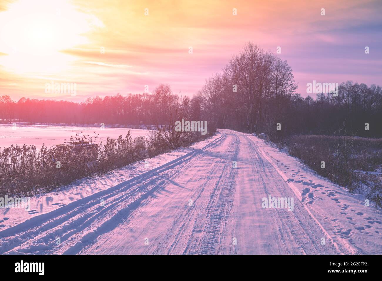 Rural winter landscape at sunrise. Snow-covered country road along the ...