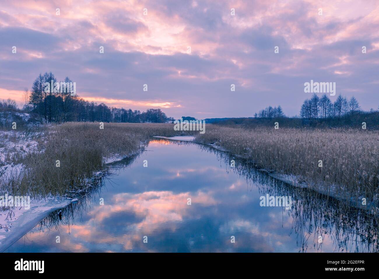 Rural landscape in winter. View of a brook and cloudy sky at sunset ...