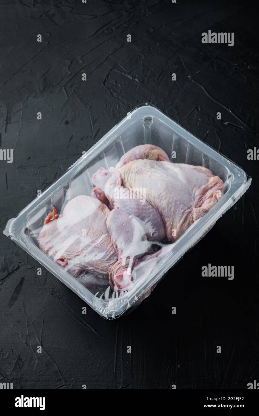 Whole raw chicken meat package, on black background with copy space for ...