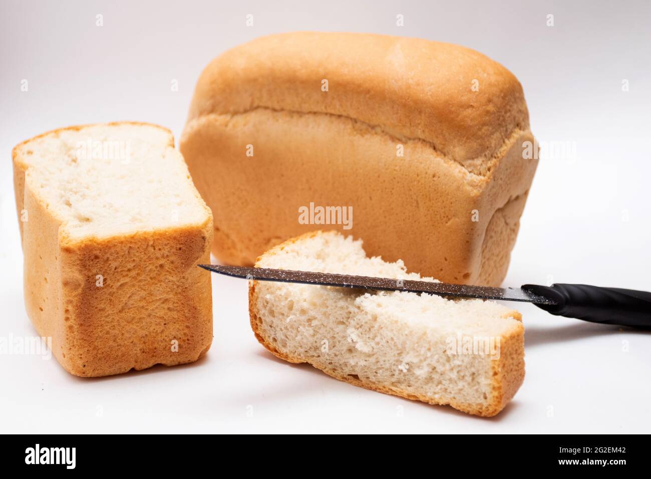 Whole grain loaf and Slices of fresh bread with knife for cut on white ...