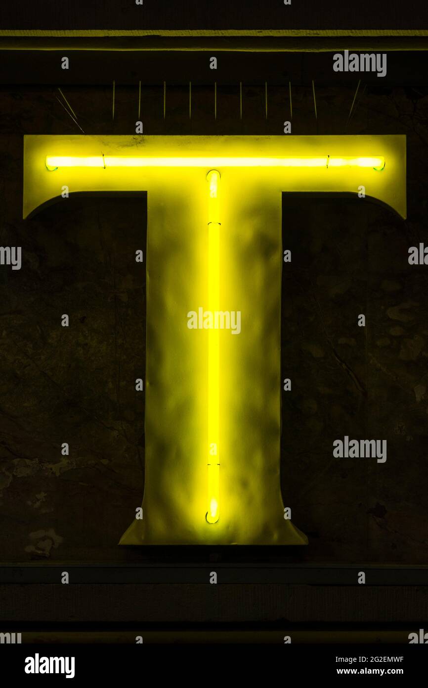 Glowing yellow neon letter T Stock Photo - Alamy