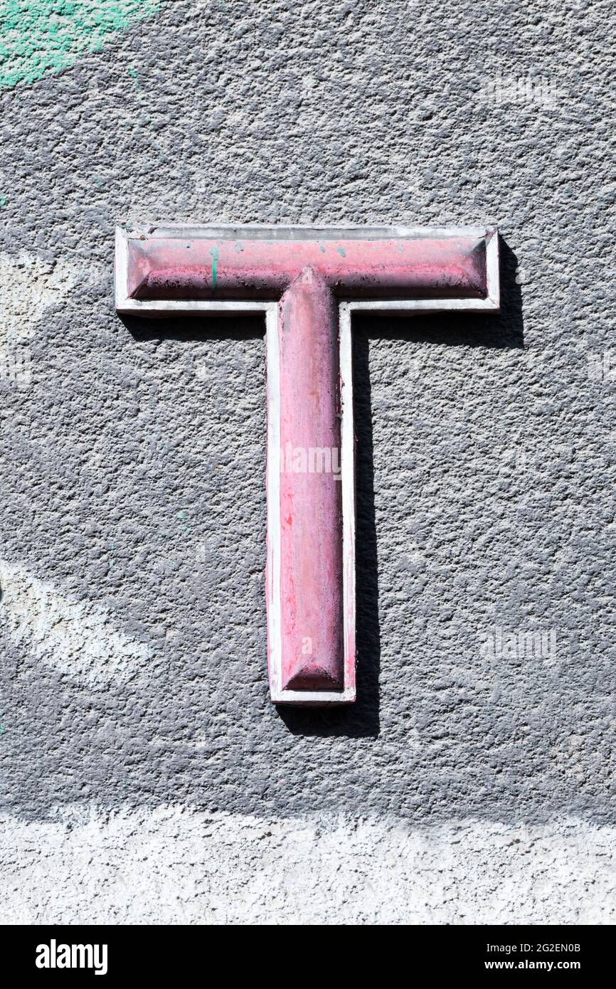 Pink letter T on colour painted house wall Stock Photo - Alamy