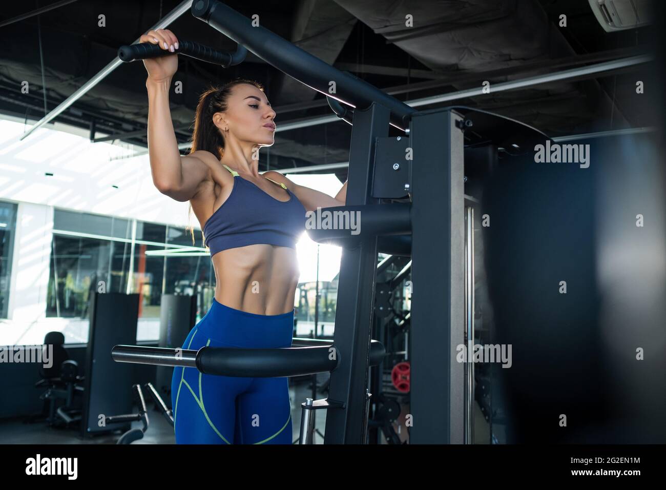 Athletic girl doing exercises on assisted pull-up machines at gym Stock ...