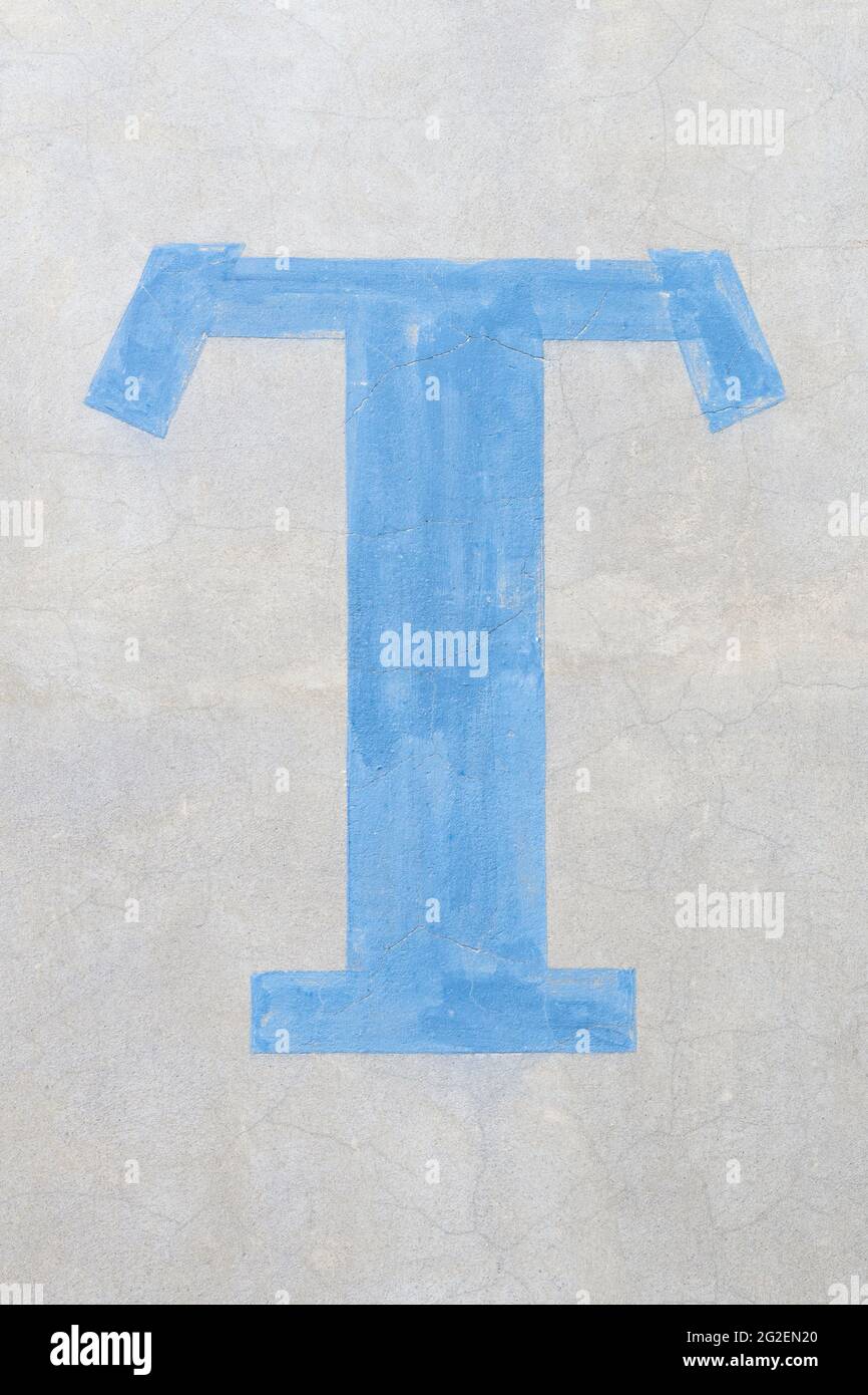 Light blue letter T in serif font on a light grey wall Stock Photo - Alamy