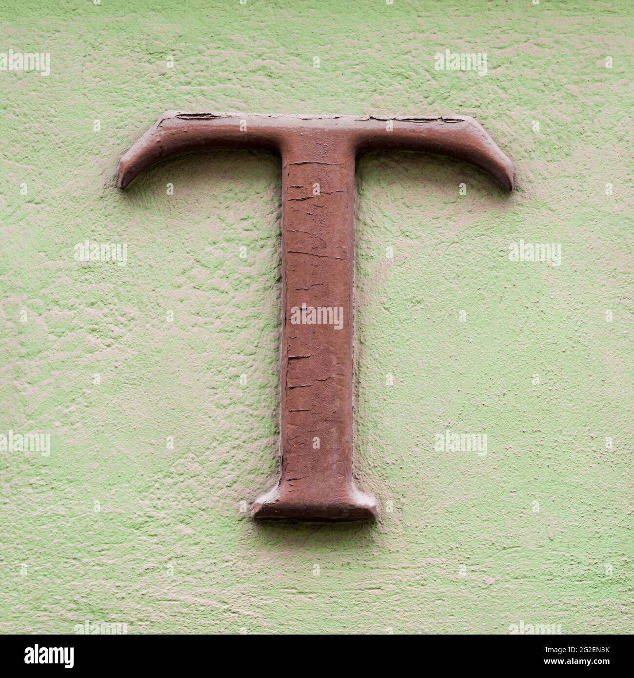 Brown letter T on green house wall Stock Photo - Alamy