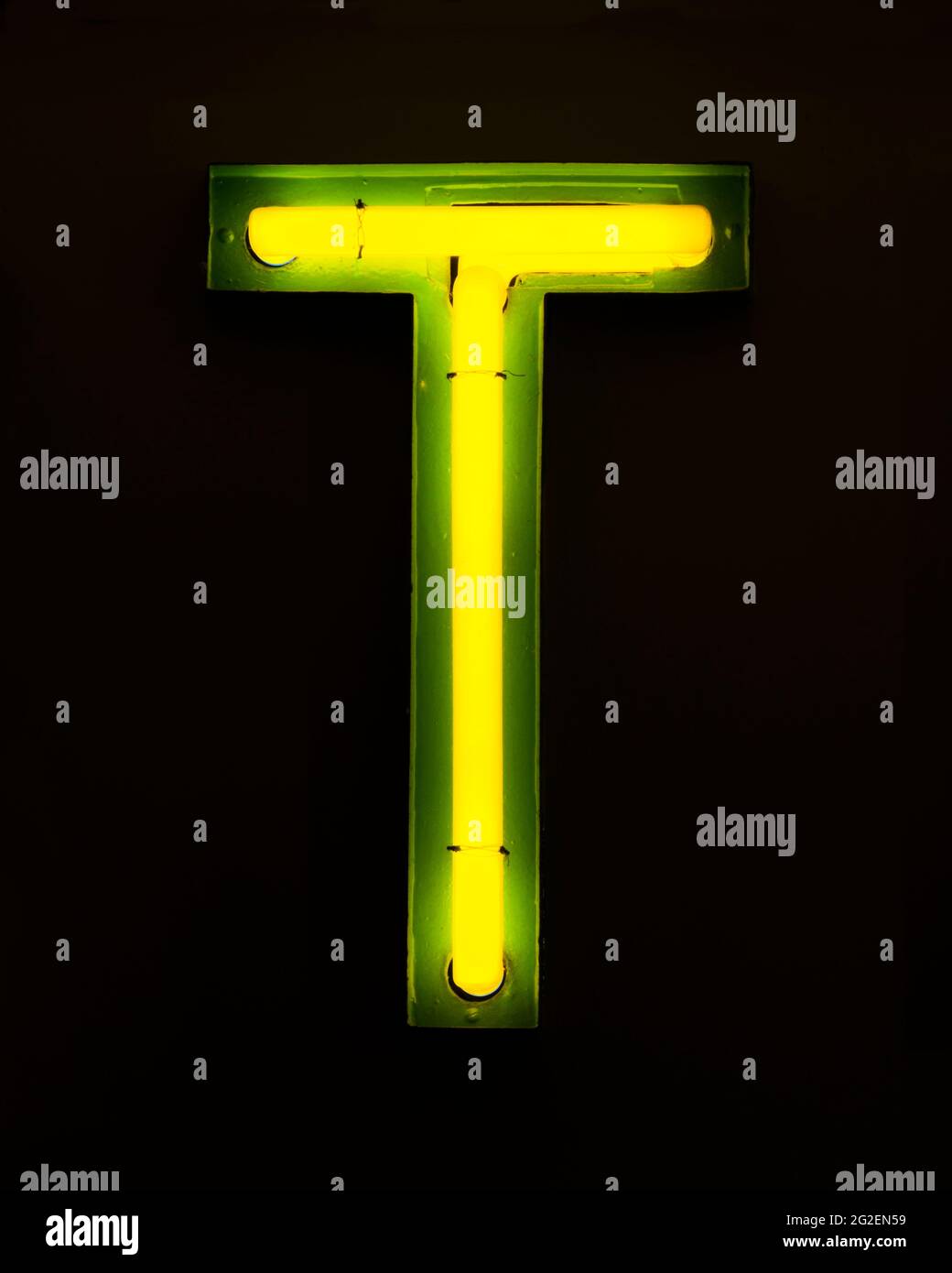 Yellow neon letter T glowing in the dark Stock Photo - Alamy