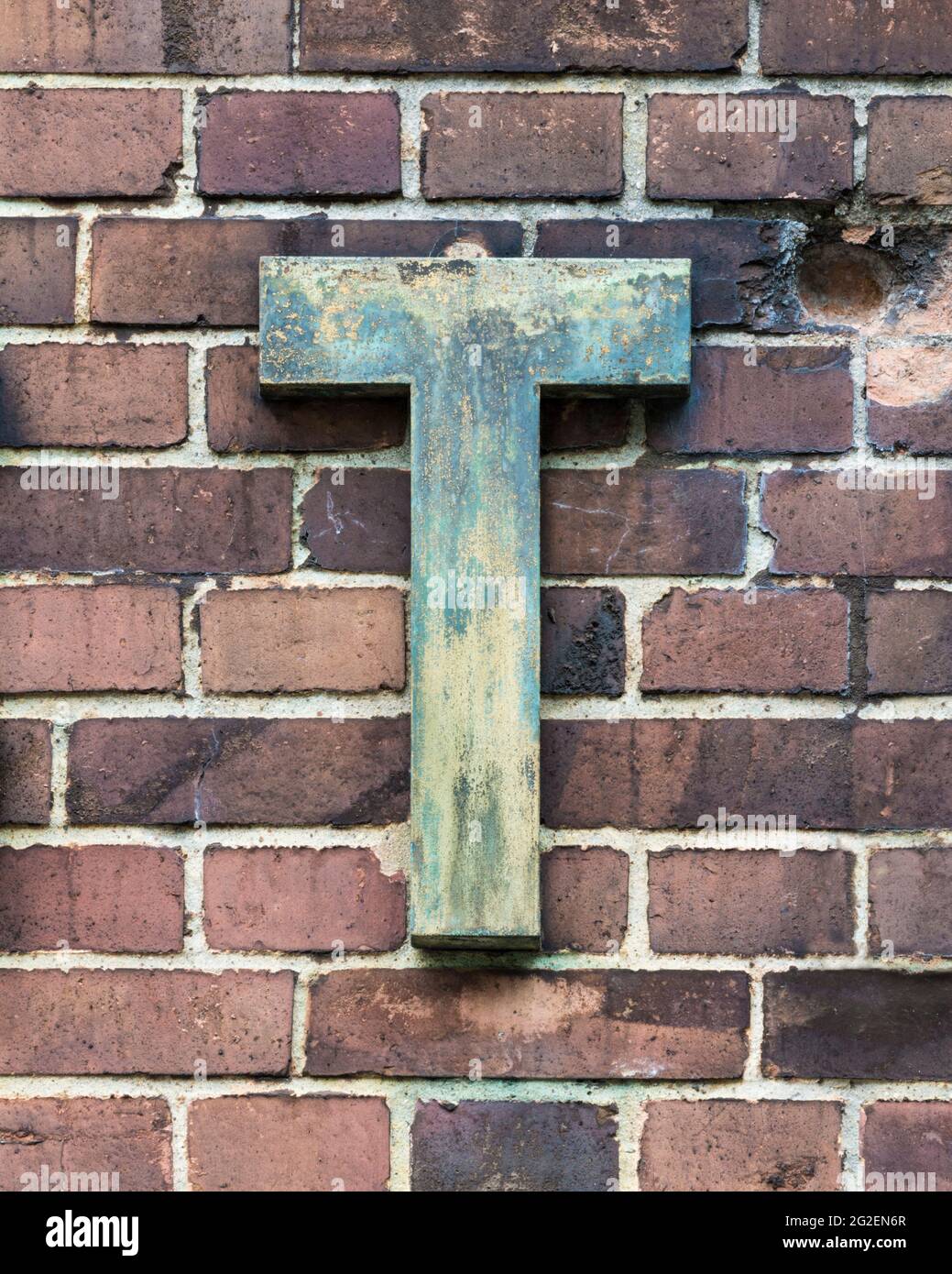 Weathered metal letter T in front of a brick wall Stock Photo - Alamy