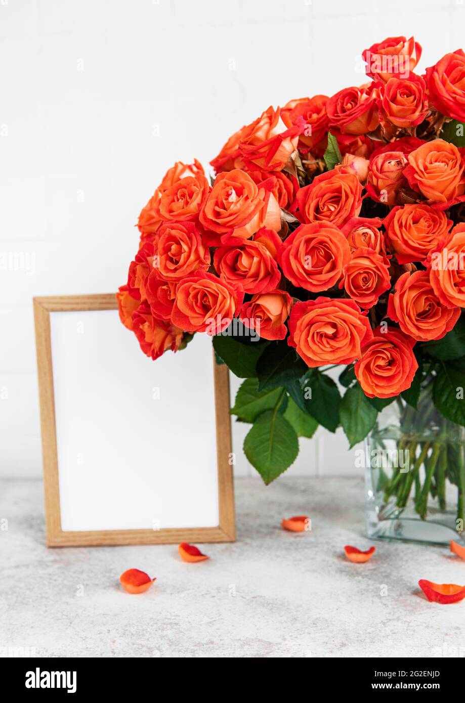 Red roses in a glass vase with an empty photo frame on the table Stock ...