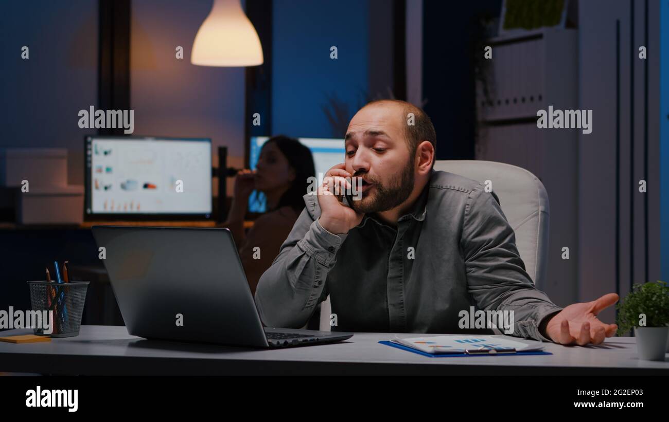 Stressed angry businessman sitting at desk table discussing corporate ...