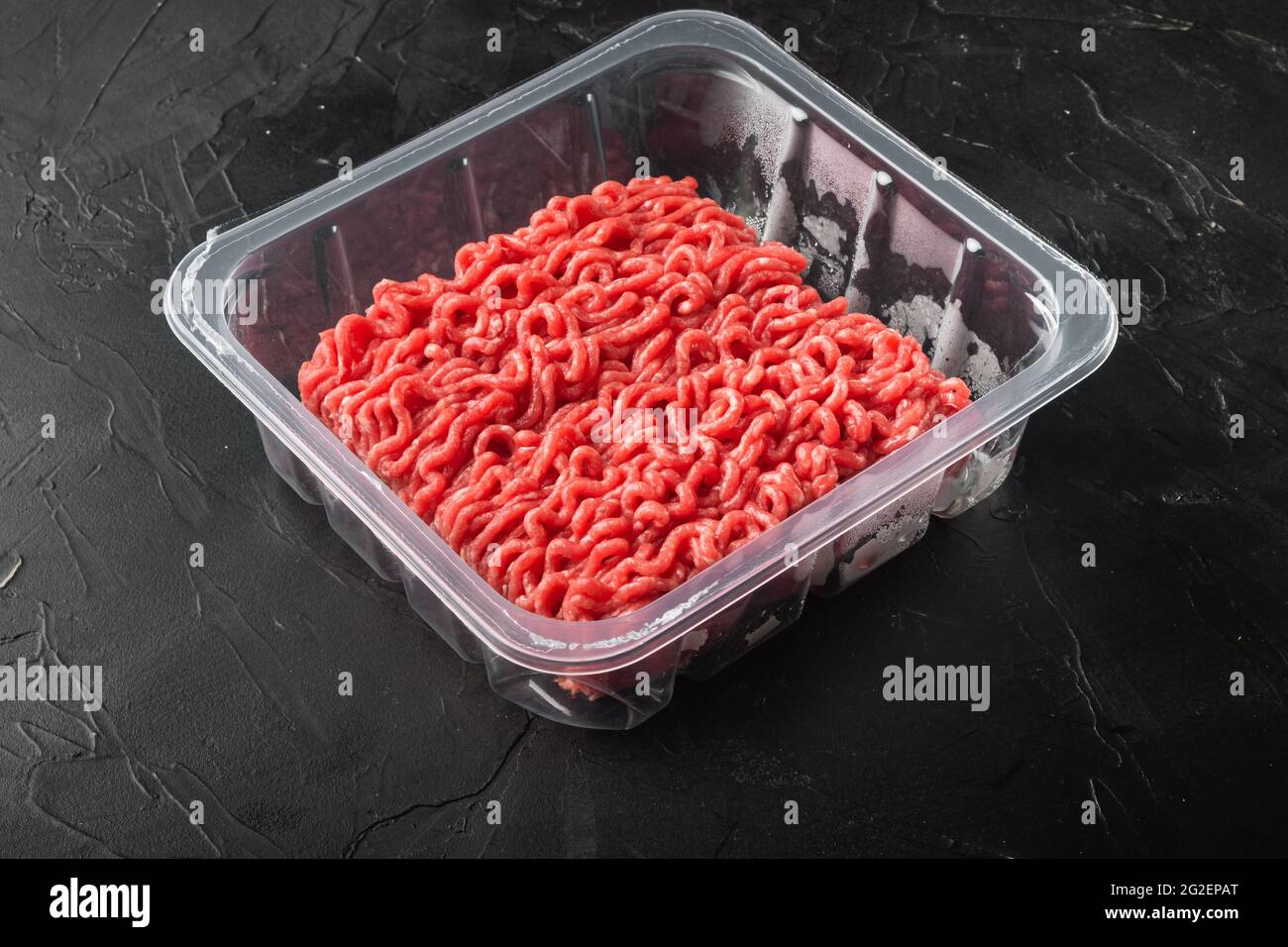 Minced meat in a transparent plastic pack set, on black stone ...