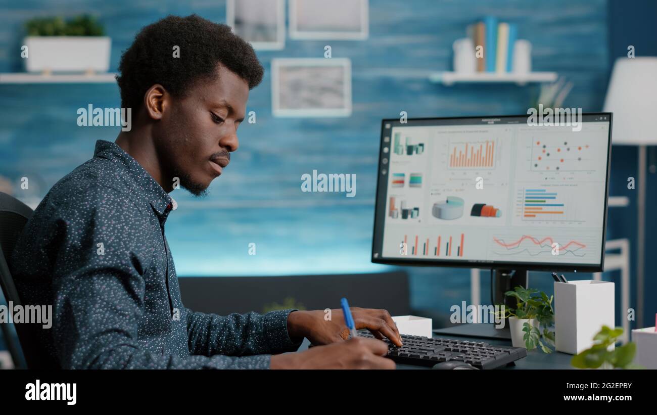 Selective focus on african american man working from home, taking notes ...