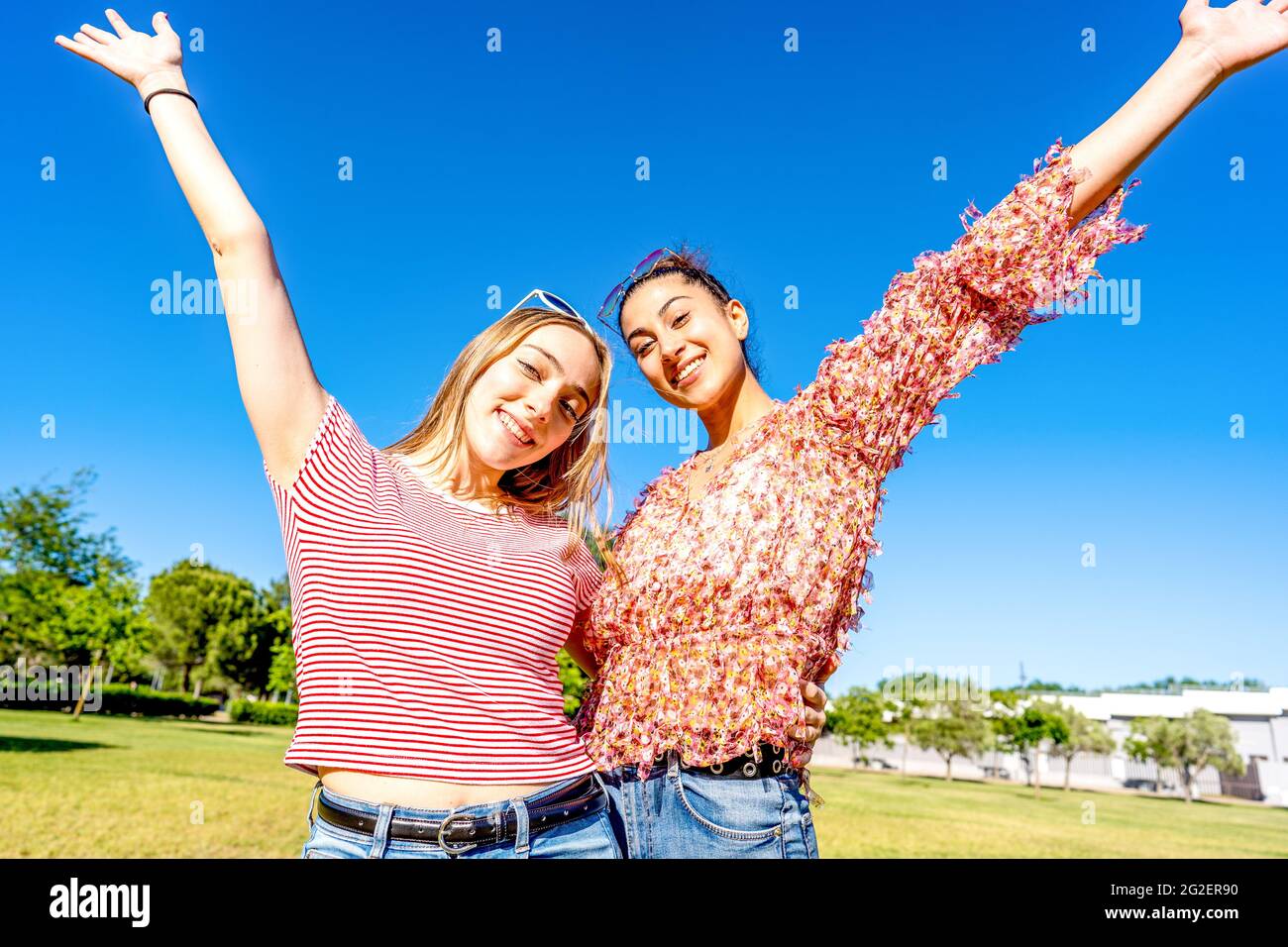 Two happy girls embracing each other with open up arms smiling looking ...