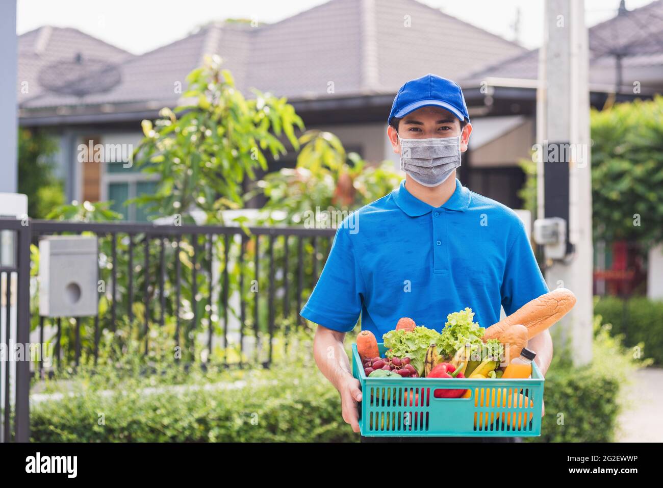 Asian grocery store delivery man wearing blue uniform and face mask ...