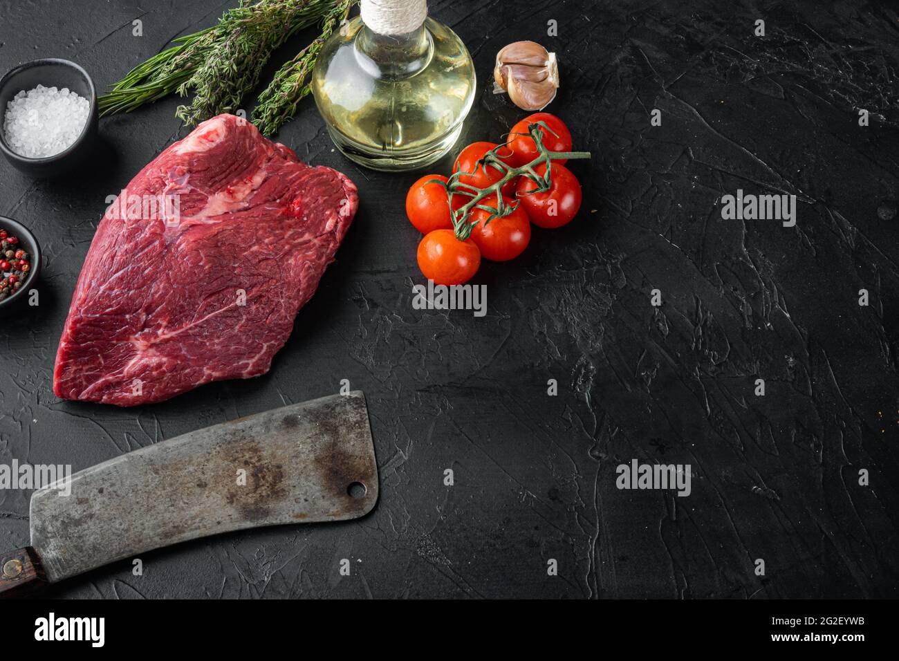 Round beef meat raw set with old butcher cleaver knife, on black ...