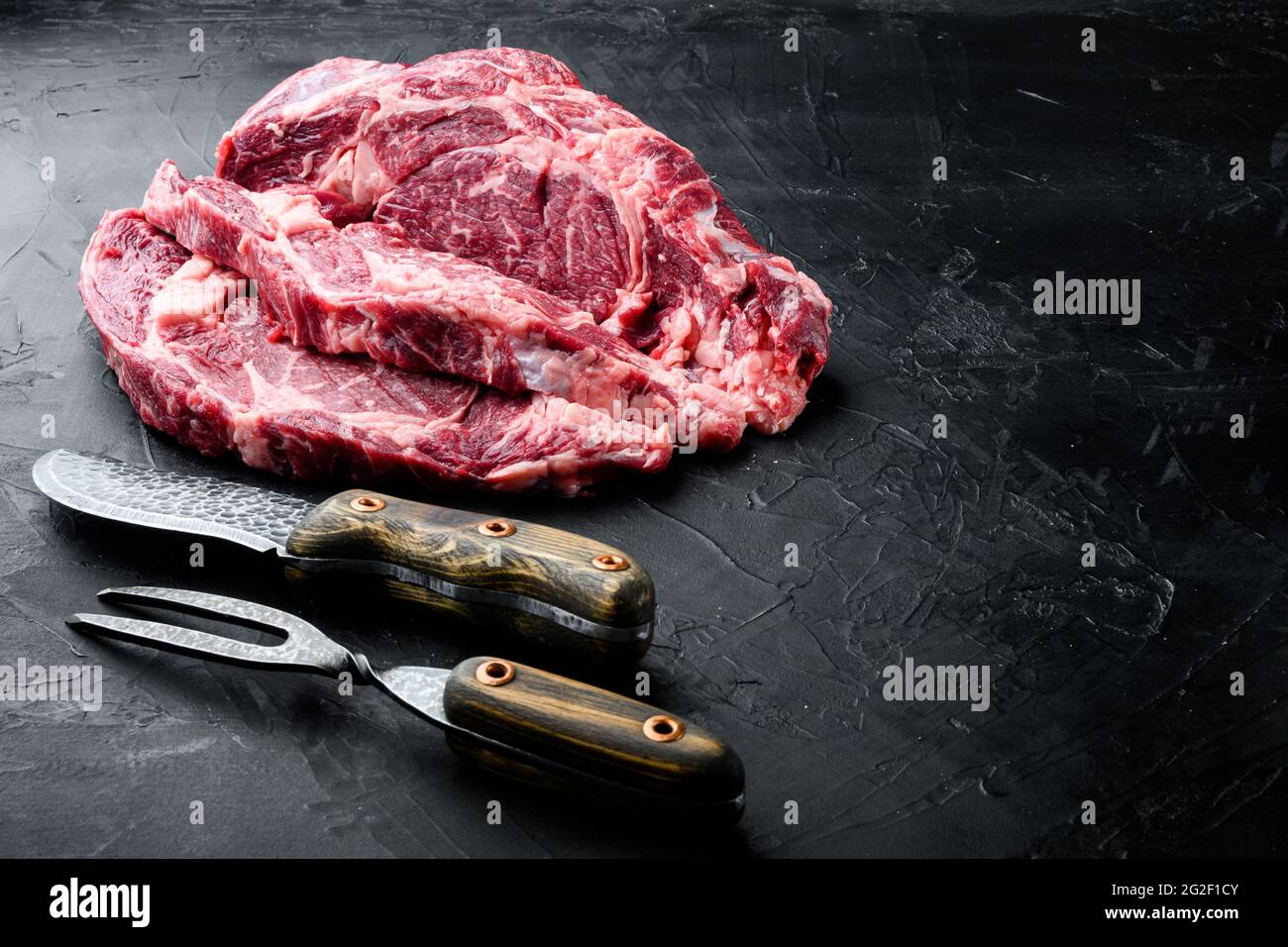 Raw marbled steak set, Rib eye cut, on black stone background Stock ...