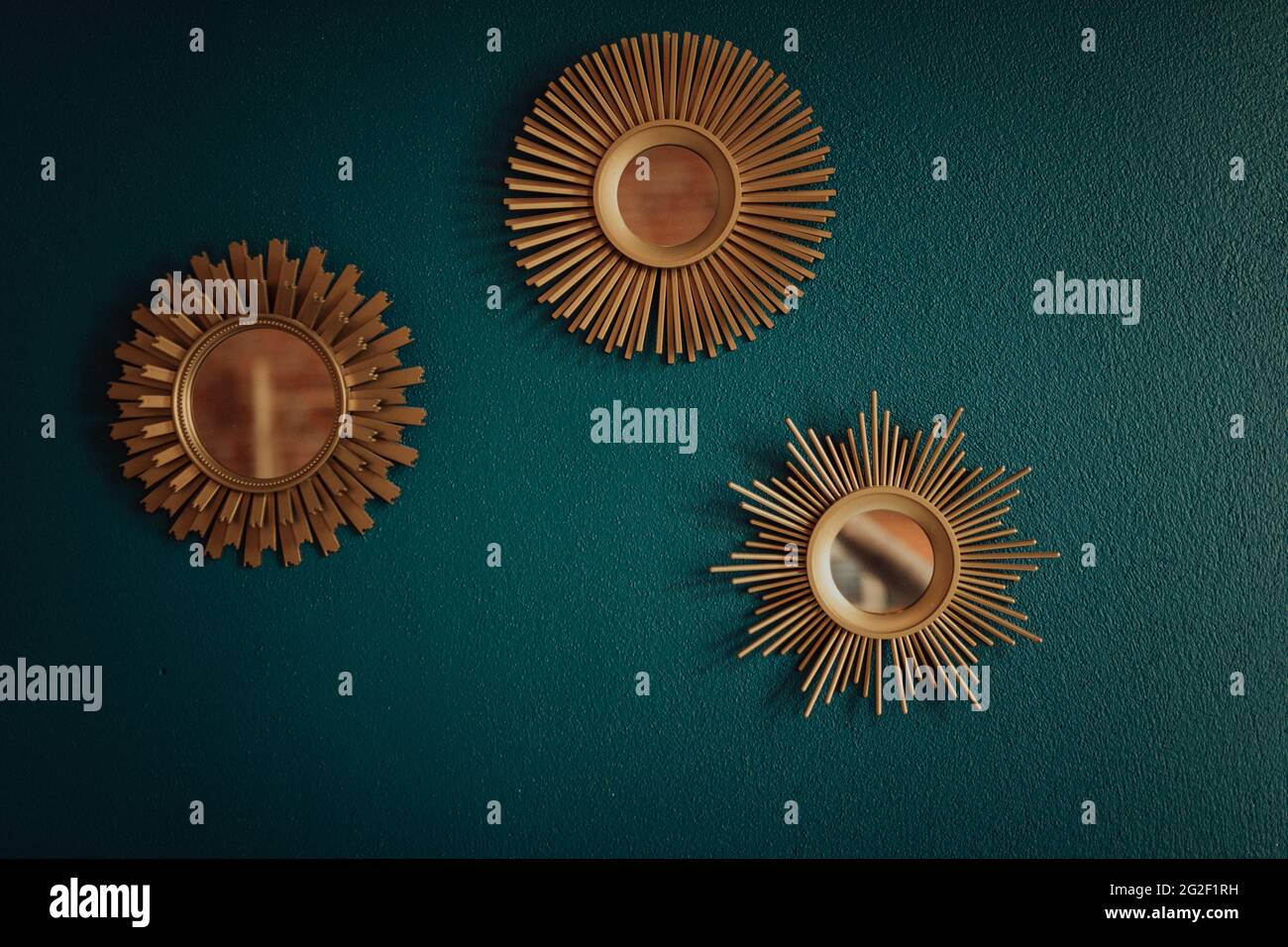 Closeup shot of three decorative, golden sun mirrors on the dark green ...