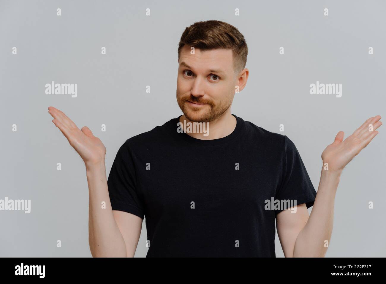 Isolated shot of confused young guy spreading hands sideways and ...