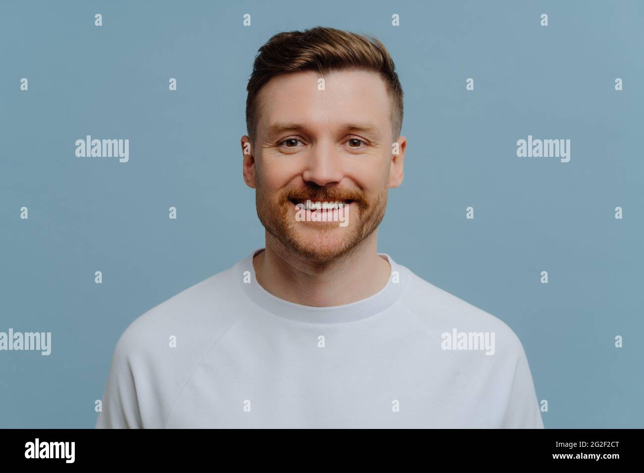Young happy handsome unshaven man in casual wear smiling at camera ...