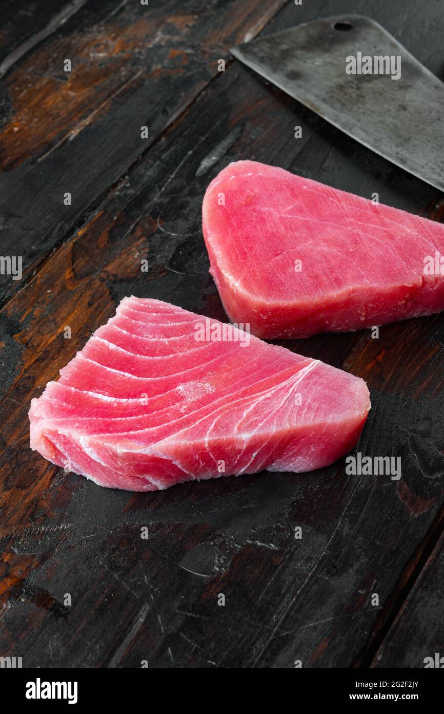 Pieces of raw tuna fish set, and old butcher cleaver knife, on old dark ...