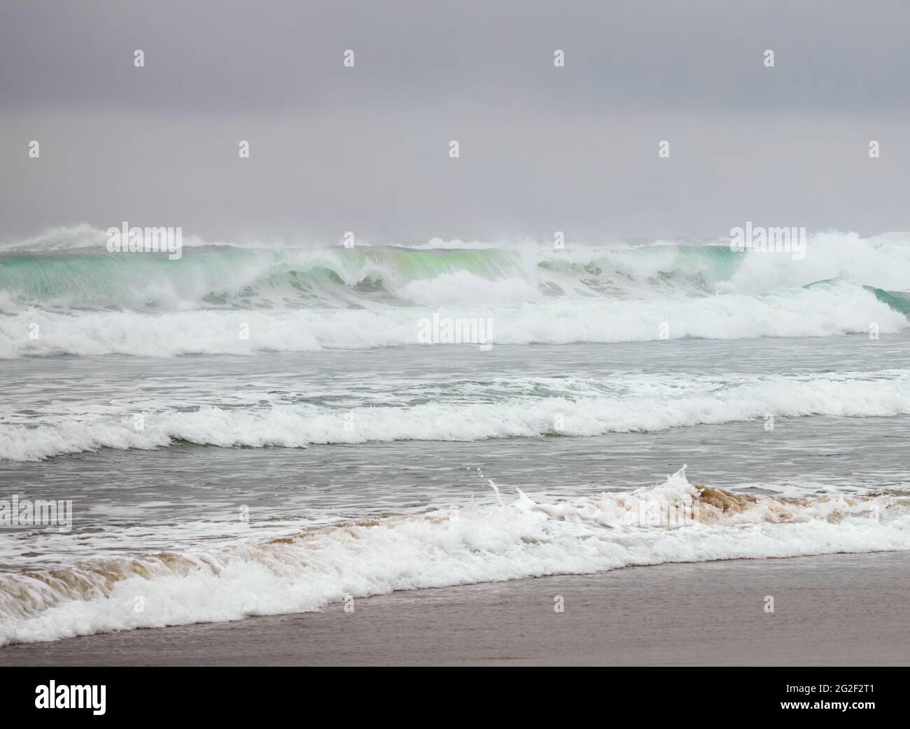 Beautiful emerald green waves of Pacific ocean hitting shoree on foggy ...