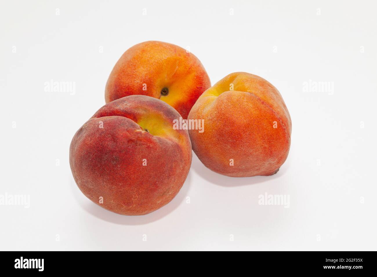Three ripe peaches clustered in the center isolated on a white ...