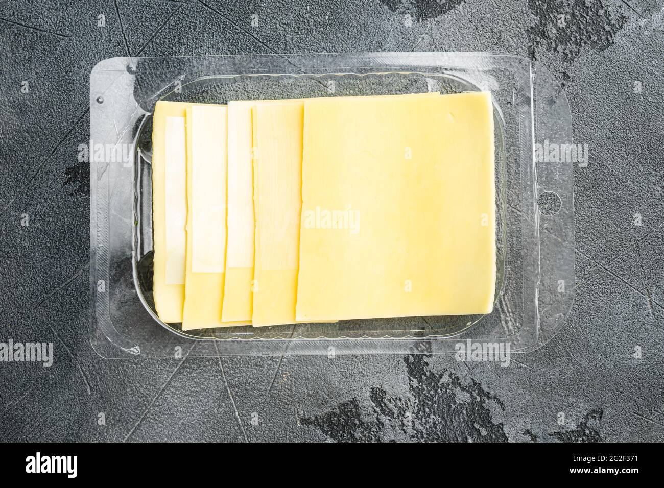 Yellow cheese slices of cheddar set, in plastic pack, on gray stone ...