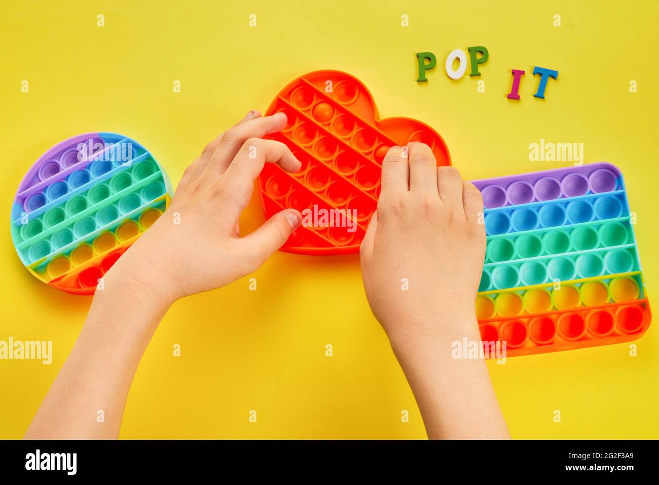 Kid hands playing with colorful pop It fidget toy. Colorful antistress ...