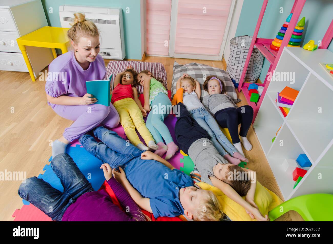Time for reading stories at the daycare Stock Photo - Alamy